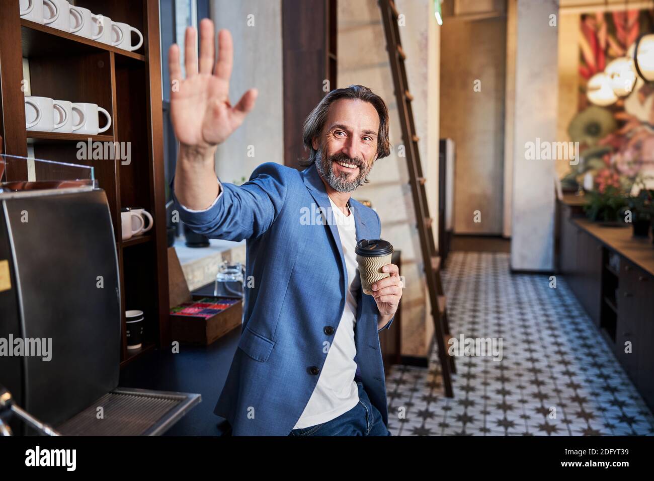 Cheerful gentleman greeting someone by the coffee machine Stock Photo ...