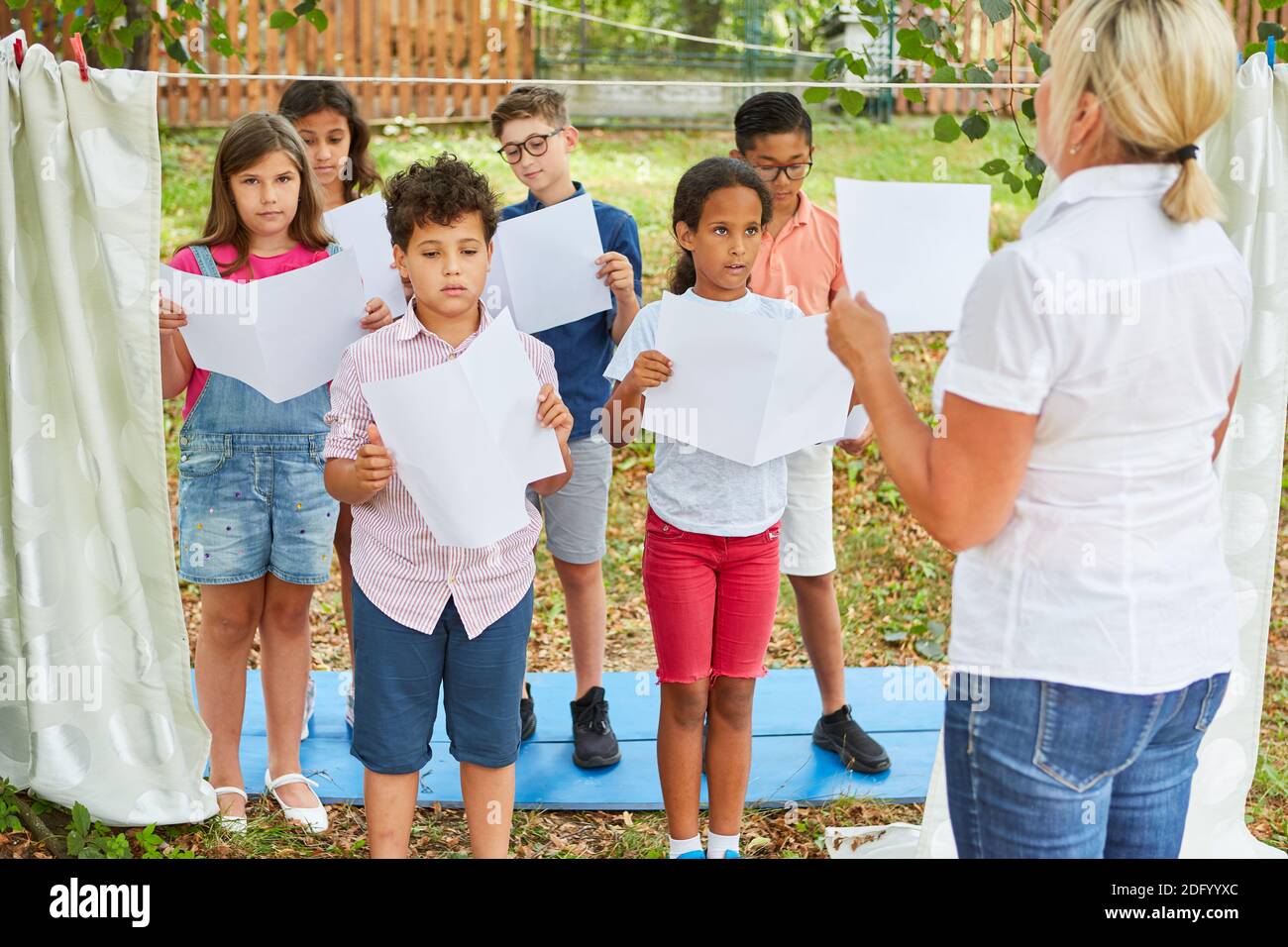 Children with music sheets sing together in a choir at holiday camp or ...