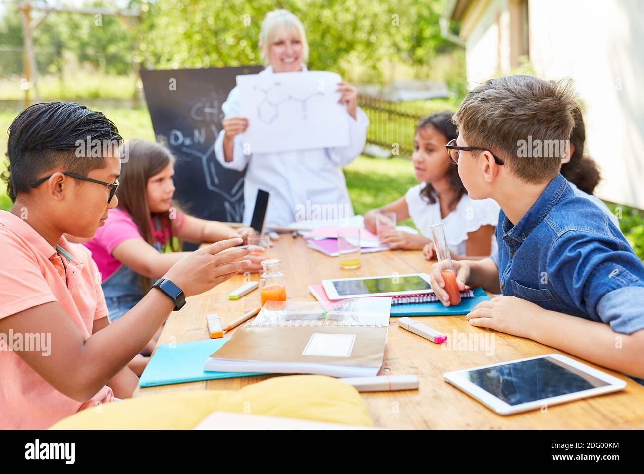 Group of children and teacher in tutoring chemistry class in summer ...