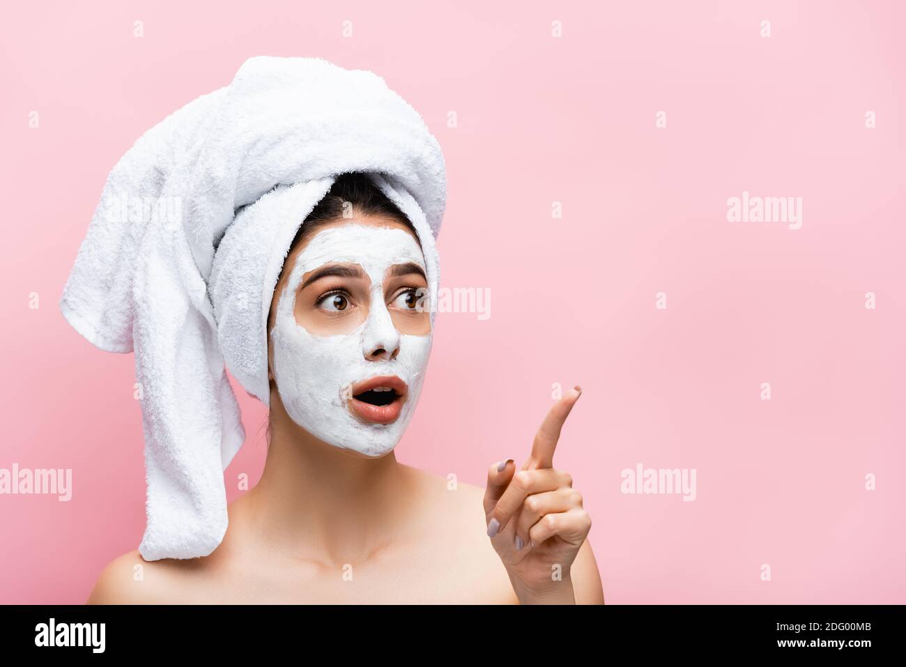 shocked beautiful woman with towel on head and clay mask on face ...