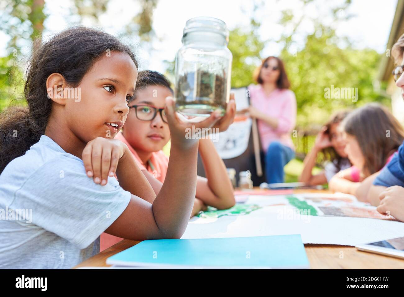 Girl with soil sample in the jar in biology class in summer school ...