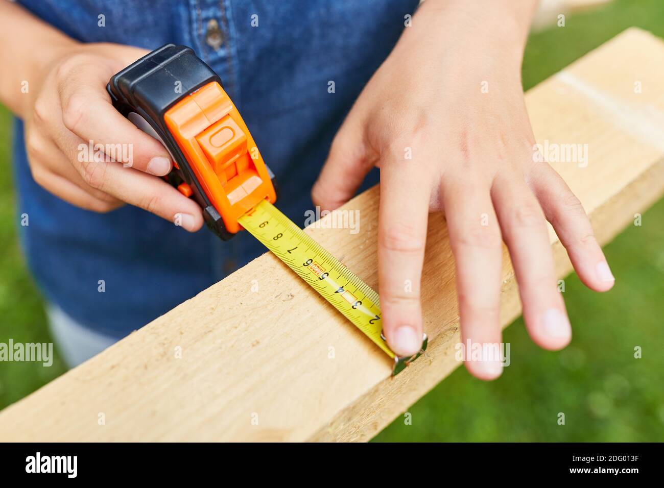 Hand of child with tape measure while measuring wood in craftsman ...