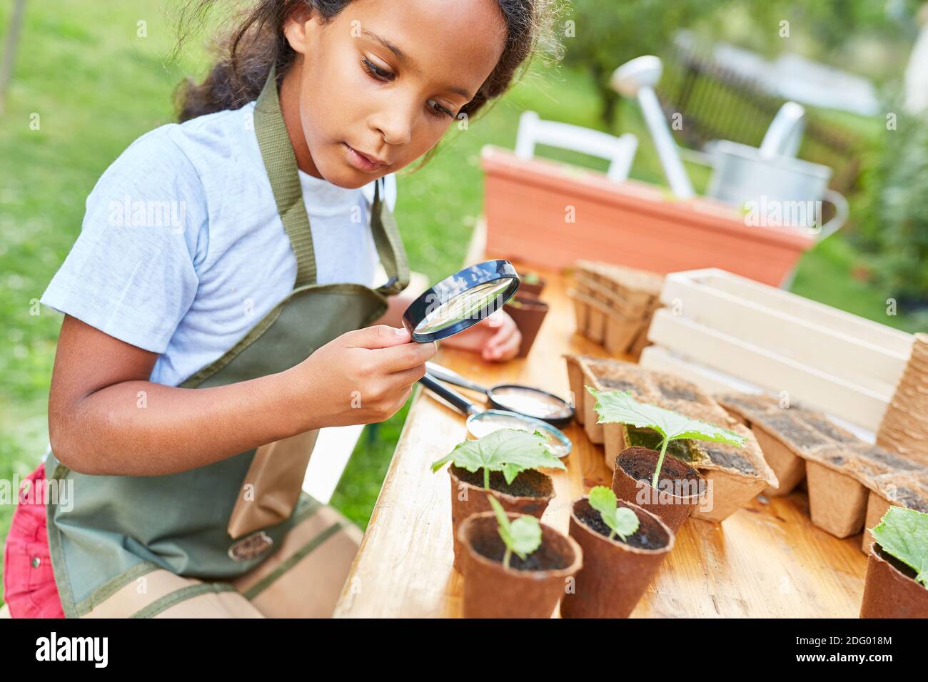 Child with plants and magnifying glass in environmental protection and ...