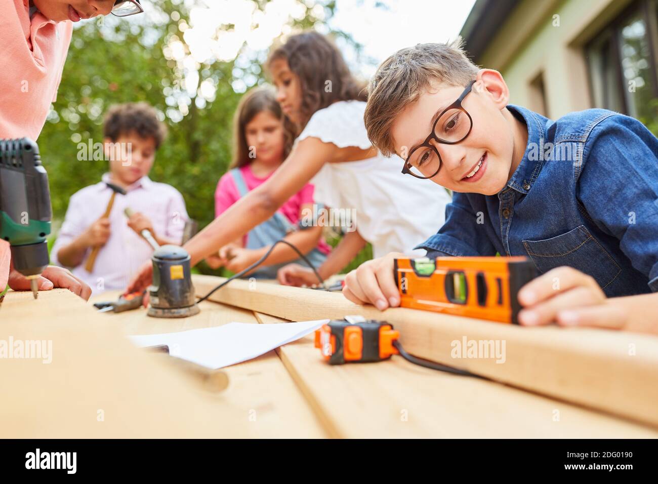 Boy with spirit level has fun working with wood in the holiday camp ...