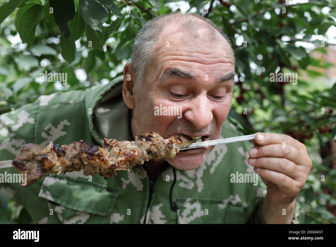Senior man eating shish kebabs on skewer at backyard Stock Photo - Alamy