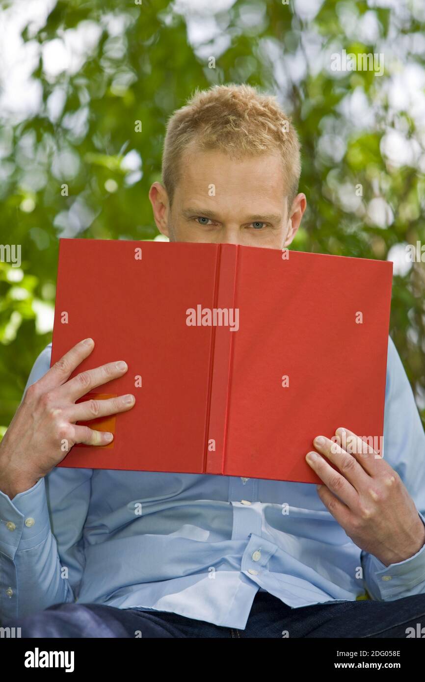 Man looks over book edge Stock Photo - Alamy