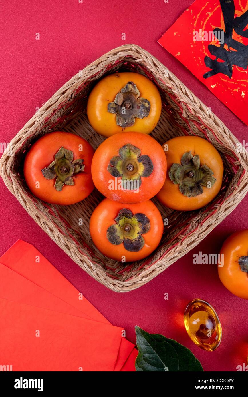 Top view of fresh sweet persimmons kaki with leaves on red table ...