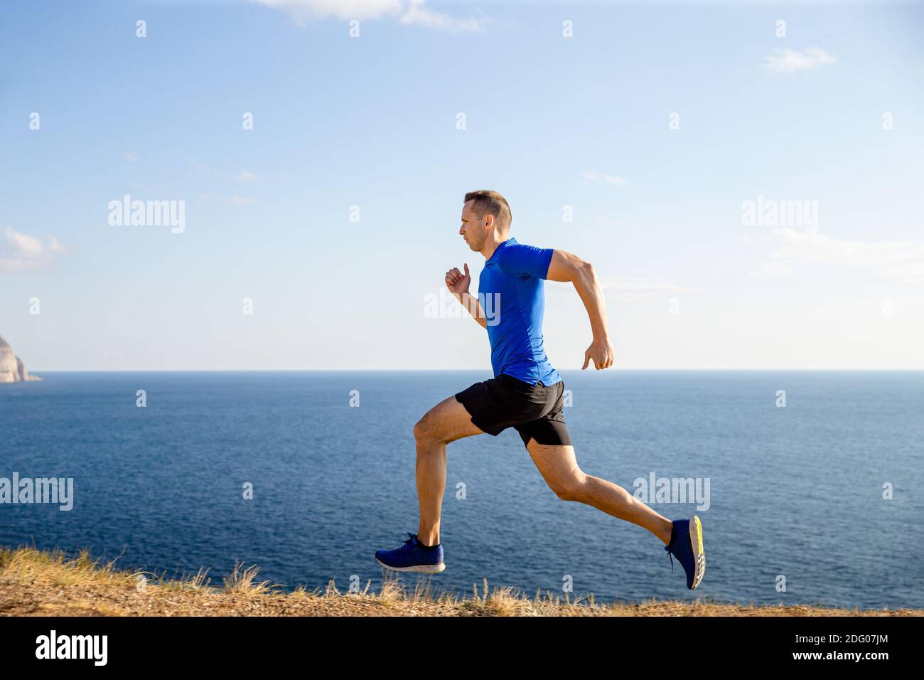 man athlete runner running trail in background blue sky and sea Stock ...