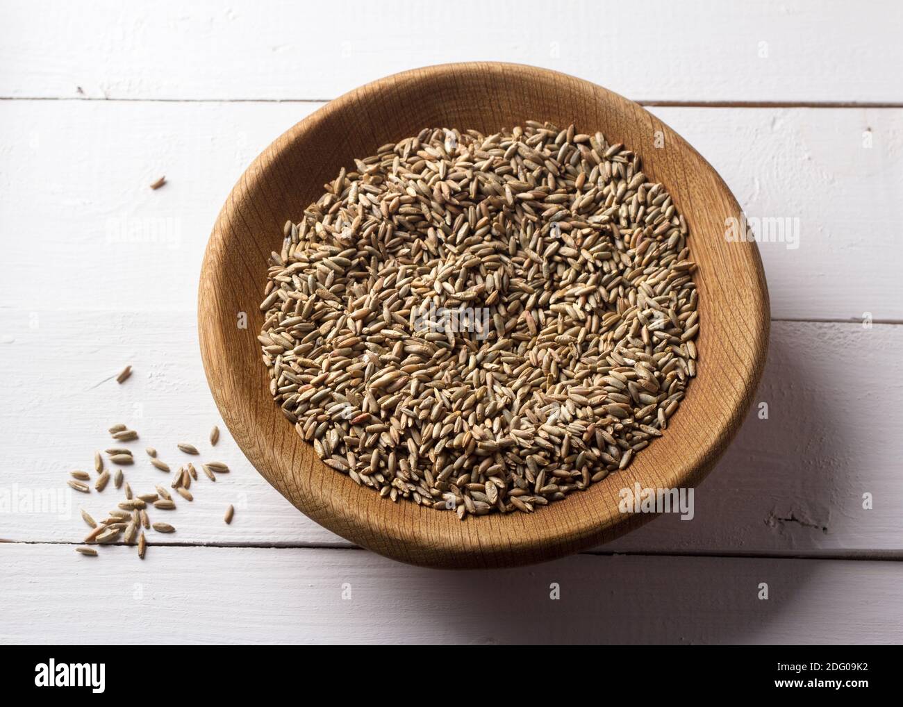 Seeds of rye for germination in a wooden bowl on a white background ...