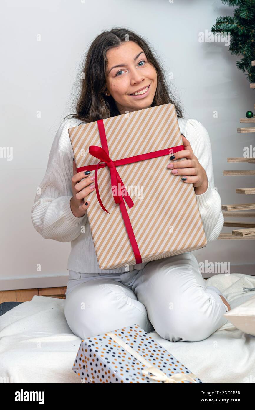 Slim Brunette In A White Knitted Jacket With A Christmas Present