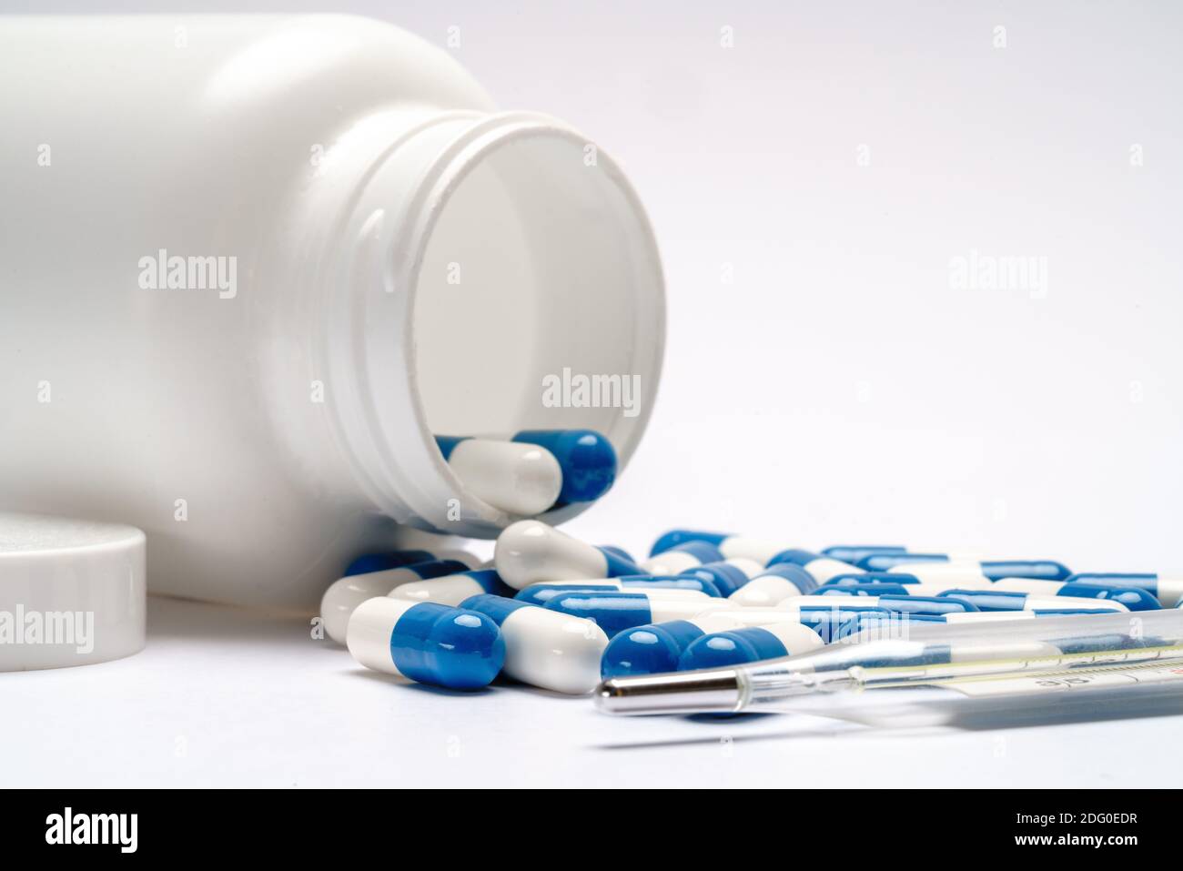 Medications capsules in a bottle and thermometer on light grey ...