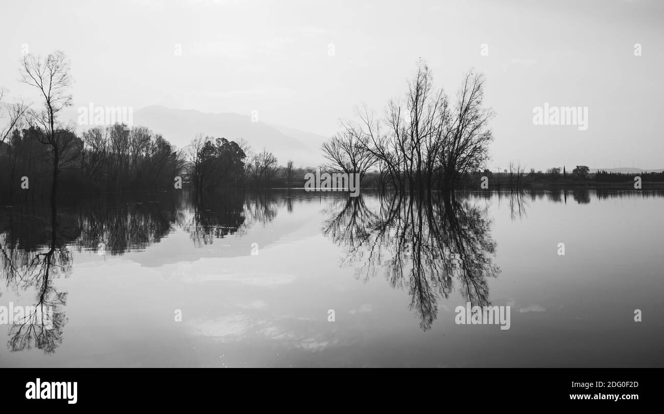 silhouette of trees and mountains reflected in the water of a lagoon at ...