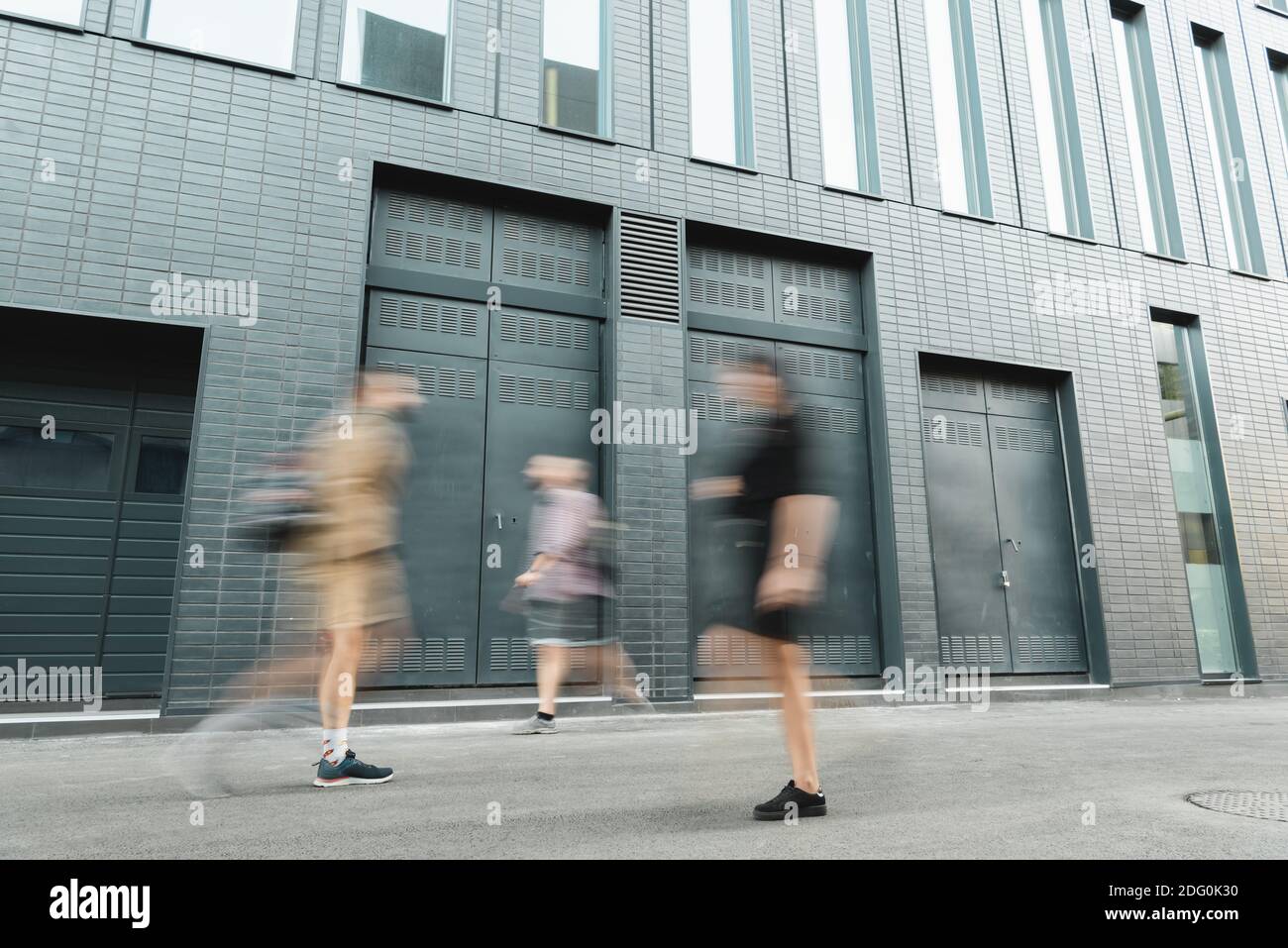 motion blur of people walking on modern street near grey building Stock ...
