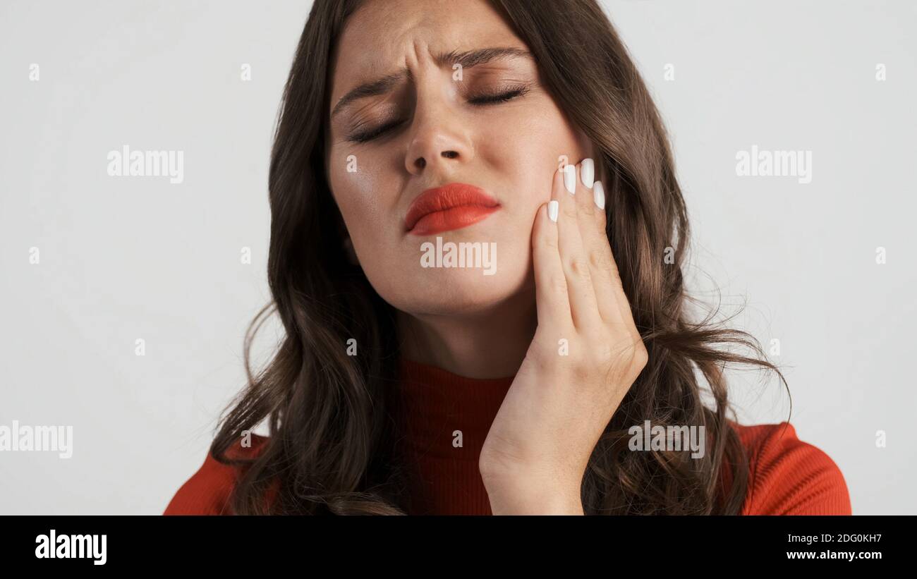 Portrait of sad girl frustratedly showing teeth pain on camera over ...