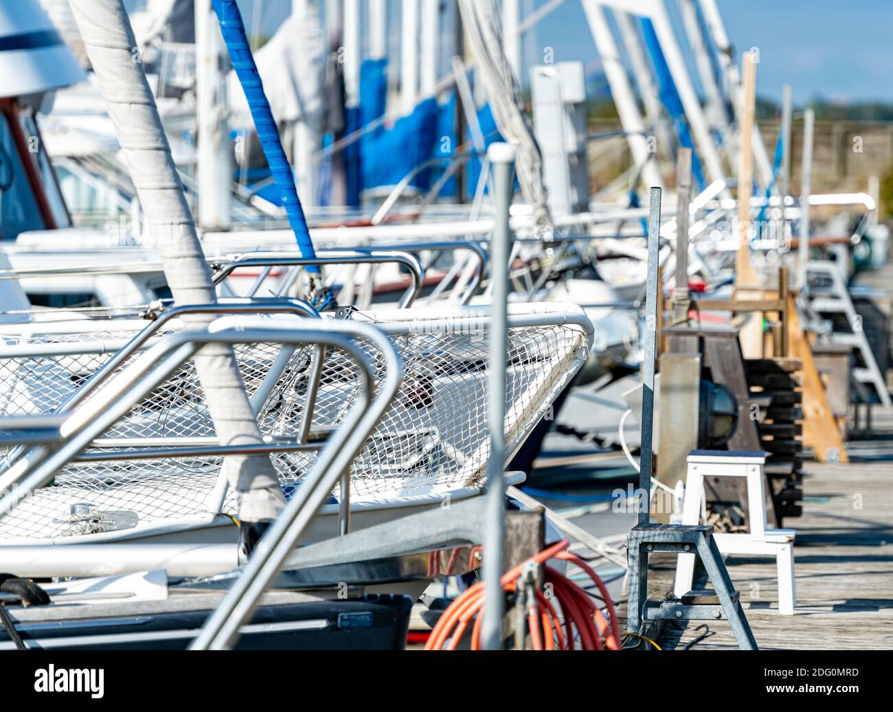 Bows of sail boats docked in a marina in the summer. Shallow depth of ...