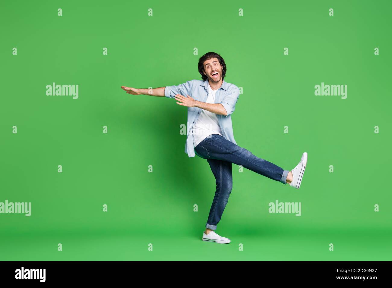 Full length photo of young stubbled guy have fun raise arms leg wear ...