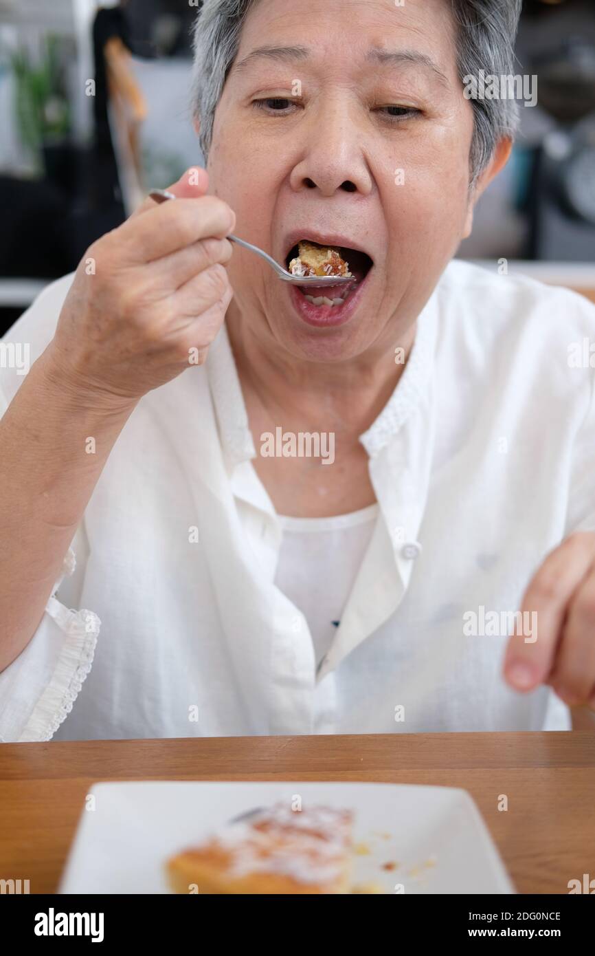 old asian elderly senior elder woman eating cake at restaurant. mature retirement lifestyle ...