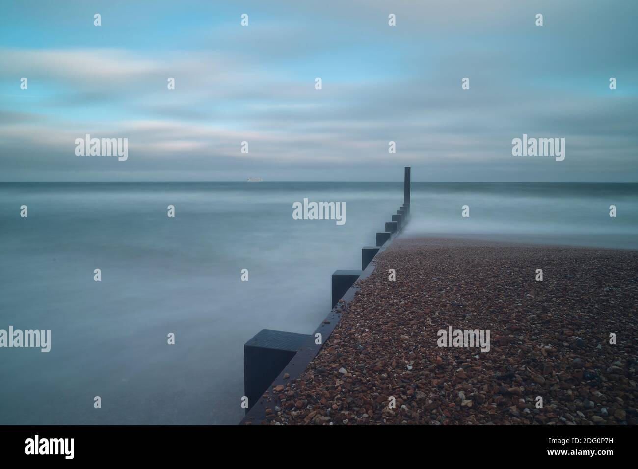 A wooden sea defence groyne marker leads out into the sea, dividing the ...