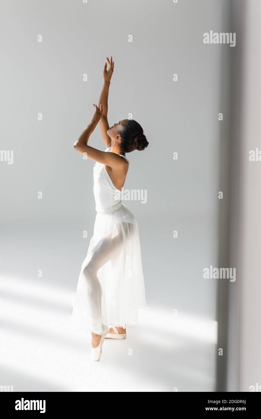 graceful african american ballerina in dress dancing on white ...