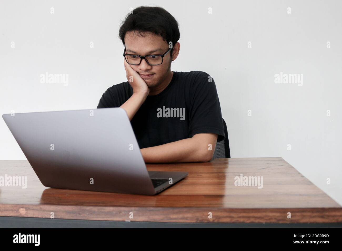 Young Asian man is boring and lazy in the front the laptop. Indonesia ...