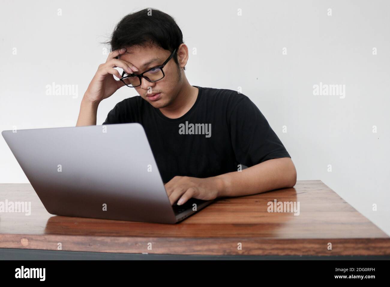 Young Asian man is boring and lazy in the front the laptop. Indonesia ...