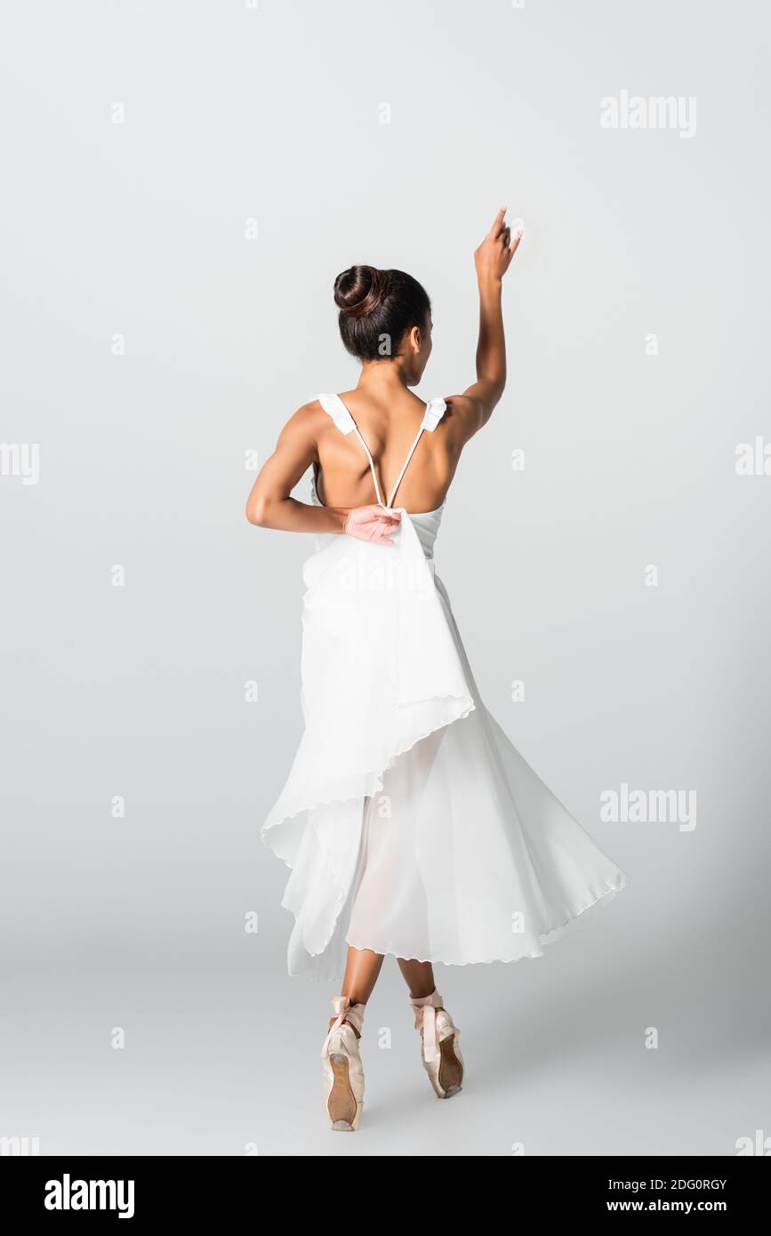 back view of graceful african american ballerina in dress dancing on ...
