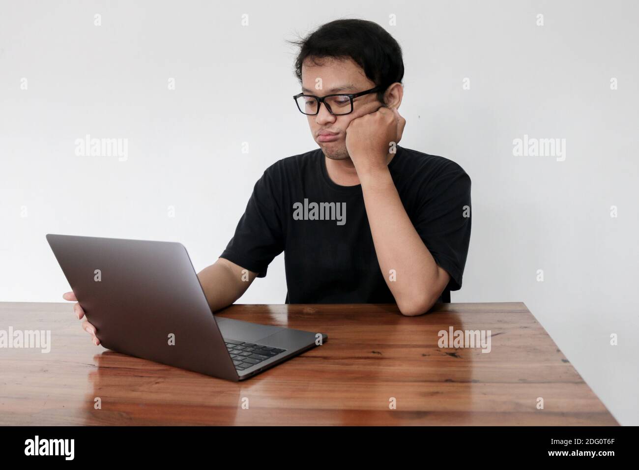Young Asian man is boring and lazy in the front the laptop. Indonesia ...