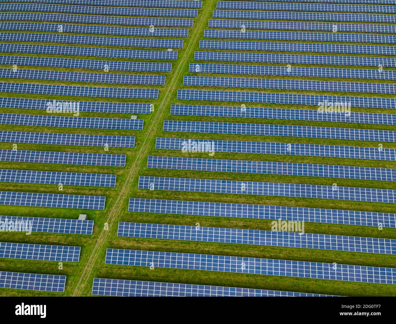 Solar power farm with long rows of modern solar panels on a grass field ...