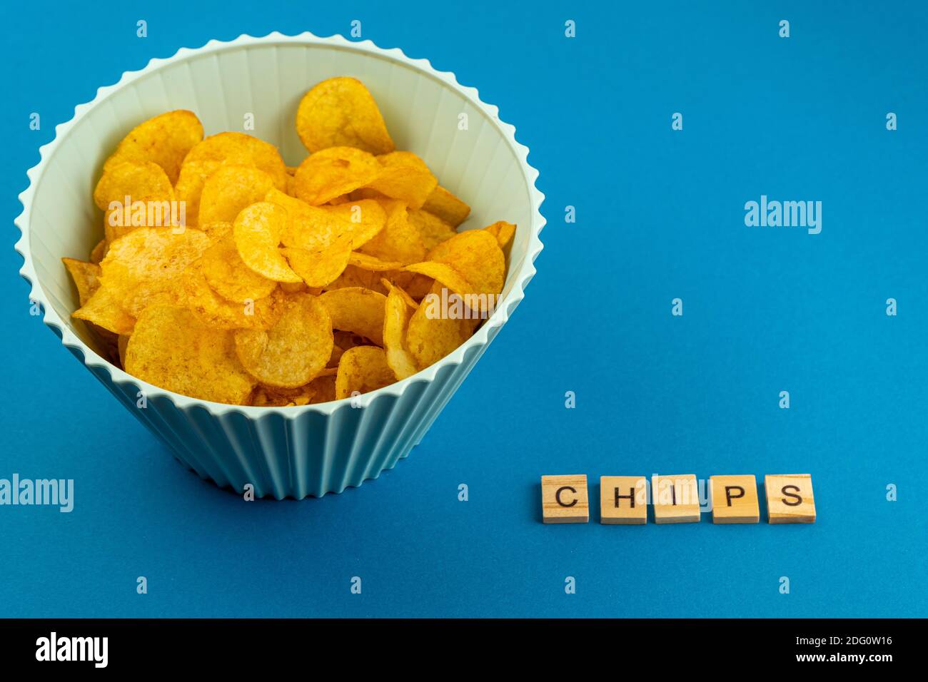 The word chips is lined with wooden letters. A bowl of potato chips on ...