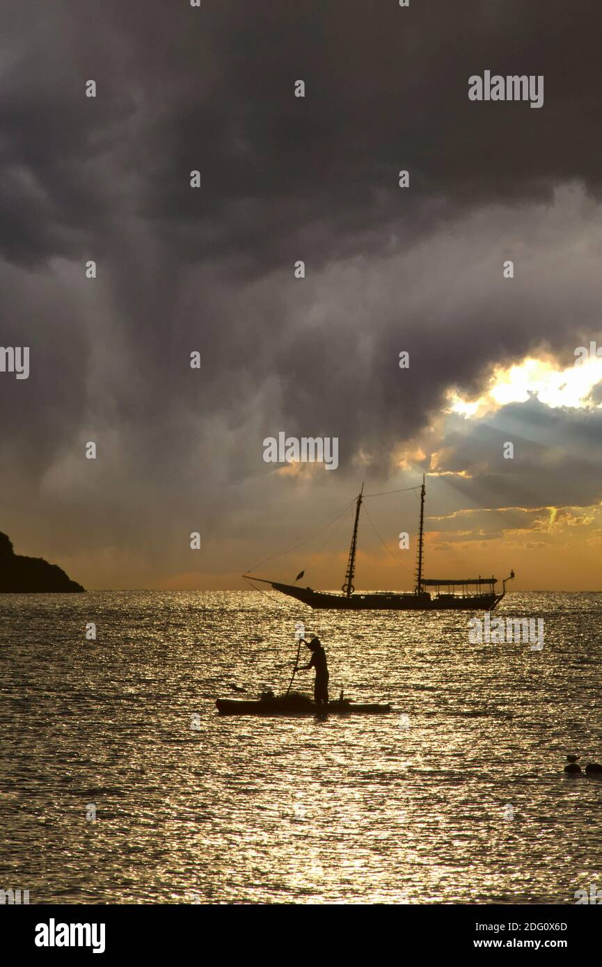 Fisherman in a row boat at sunset Stock Photo - Alamy