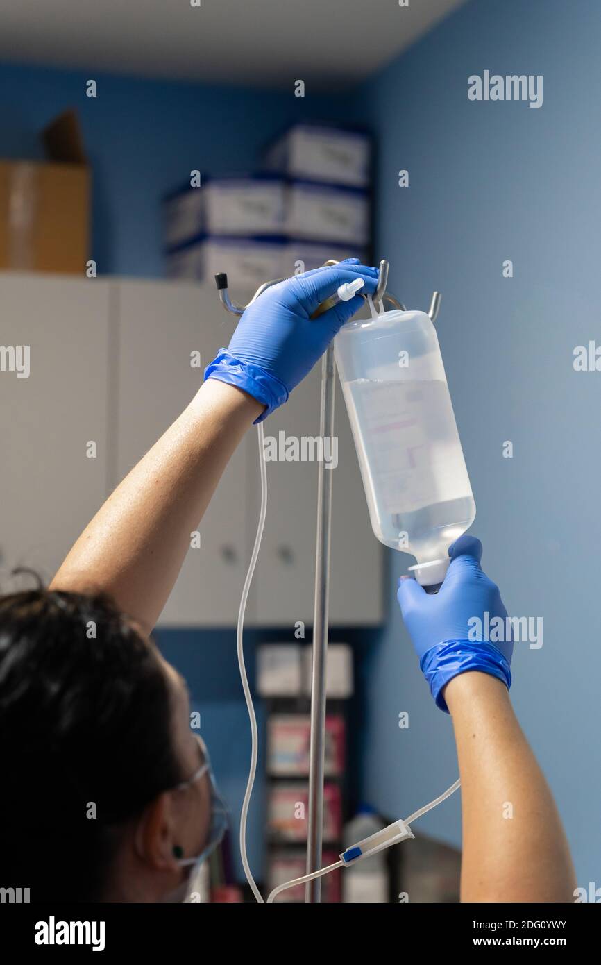 Nurse placing physiological saline solution in a serum hanger Stock ...