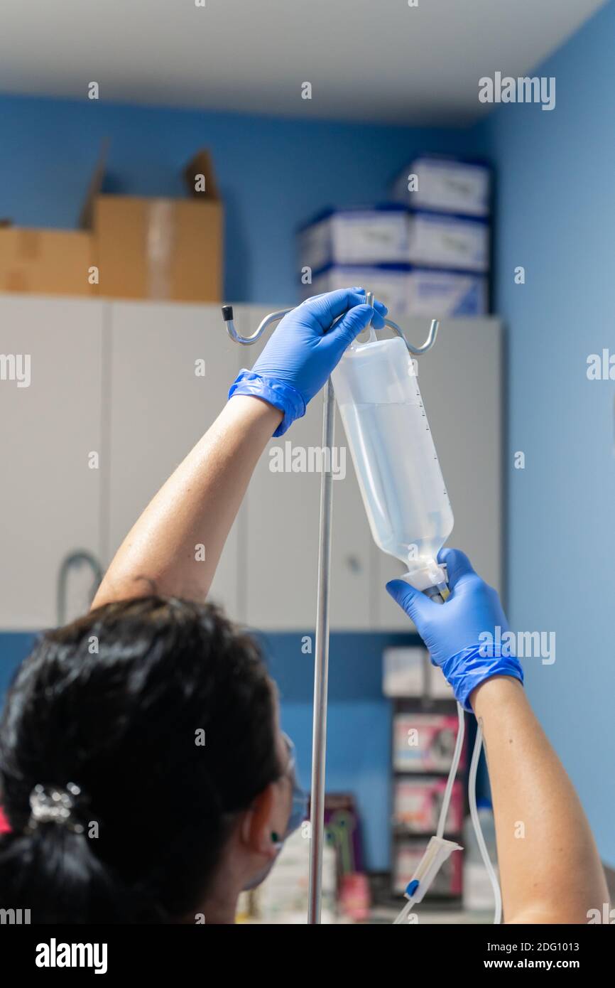 Nurse placing physiological saline solution in a serum hanger Stock ...