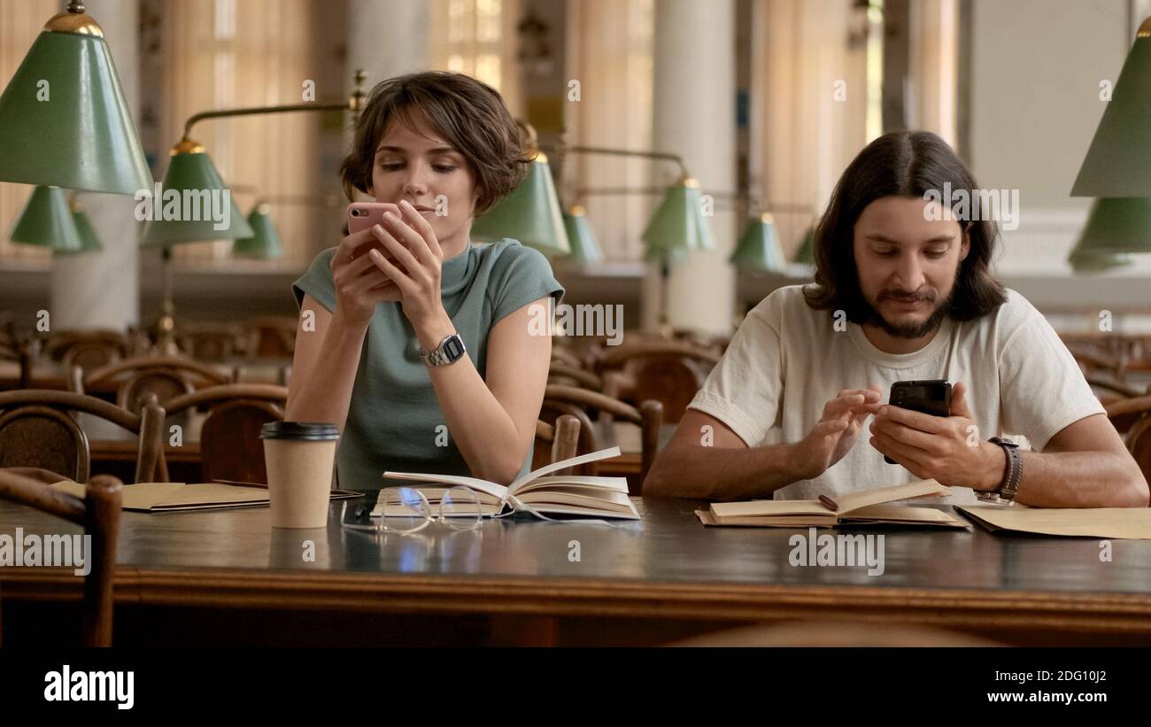 Two young students intently using smartphones while preparing for exams ...