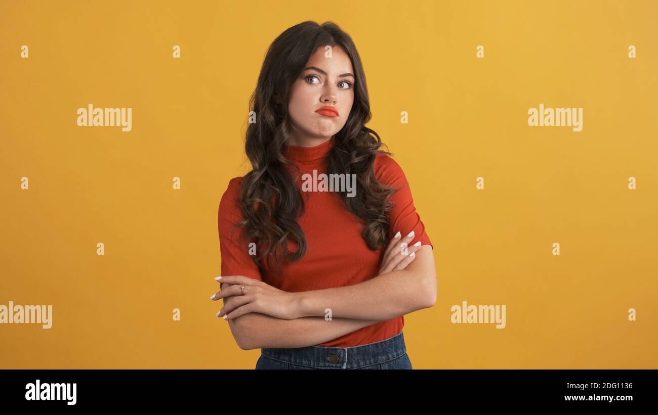 Casual bored girl in red top with hands crossed thoughtfully looking ...