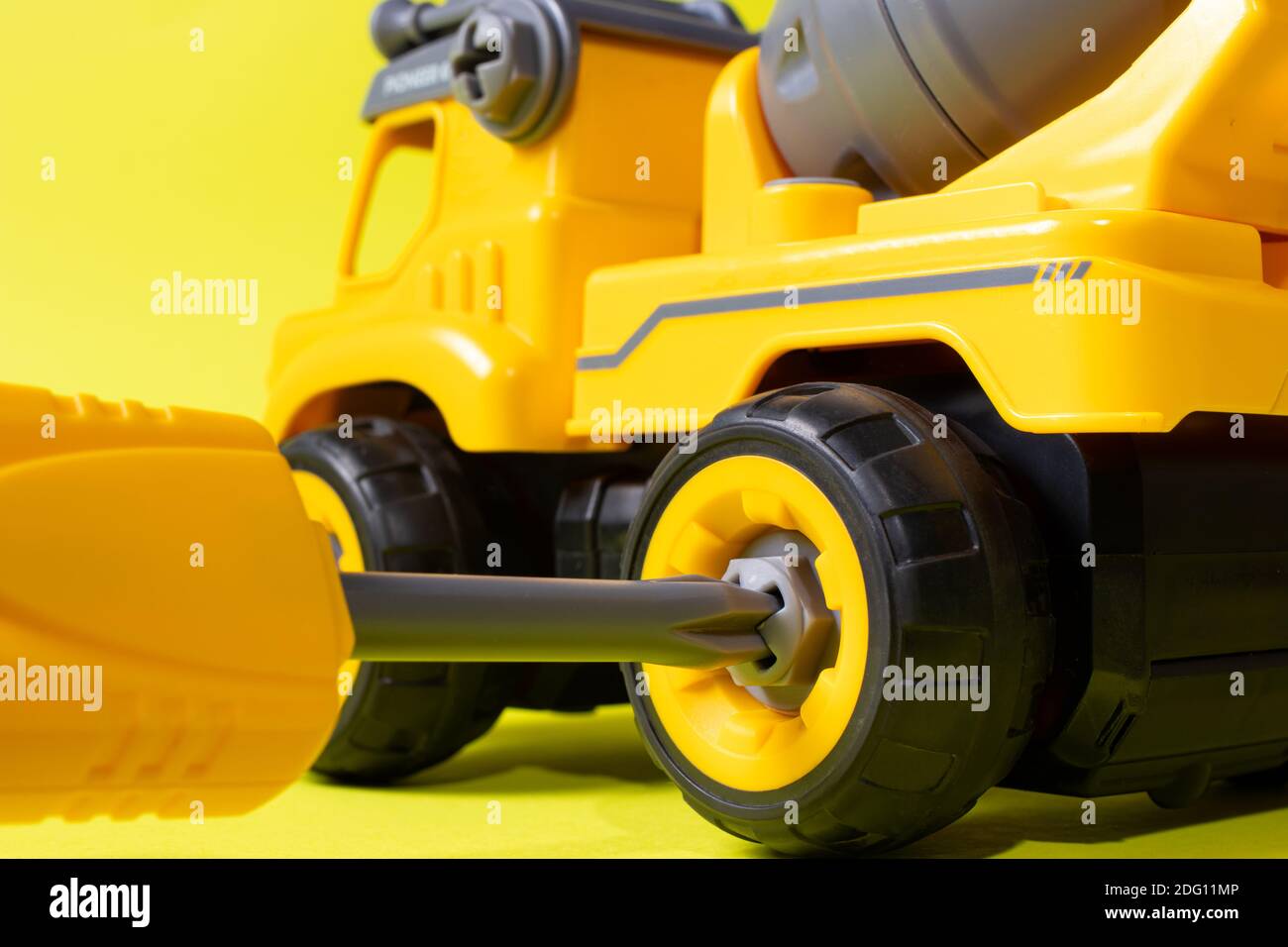 The screwdriver unscrews the wheel of the toy car on a yellow ...