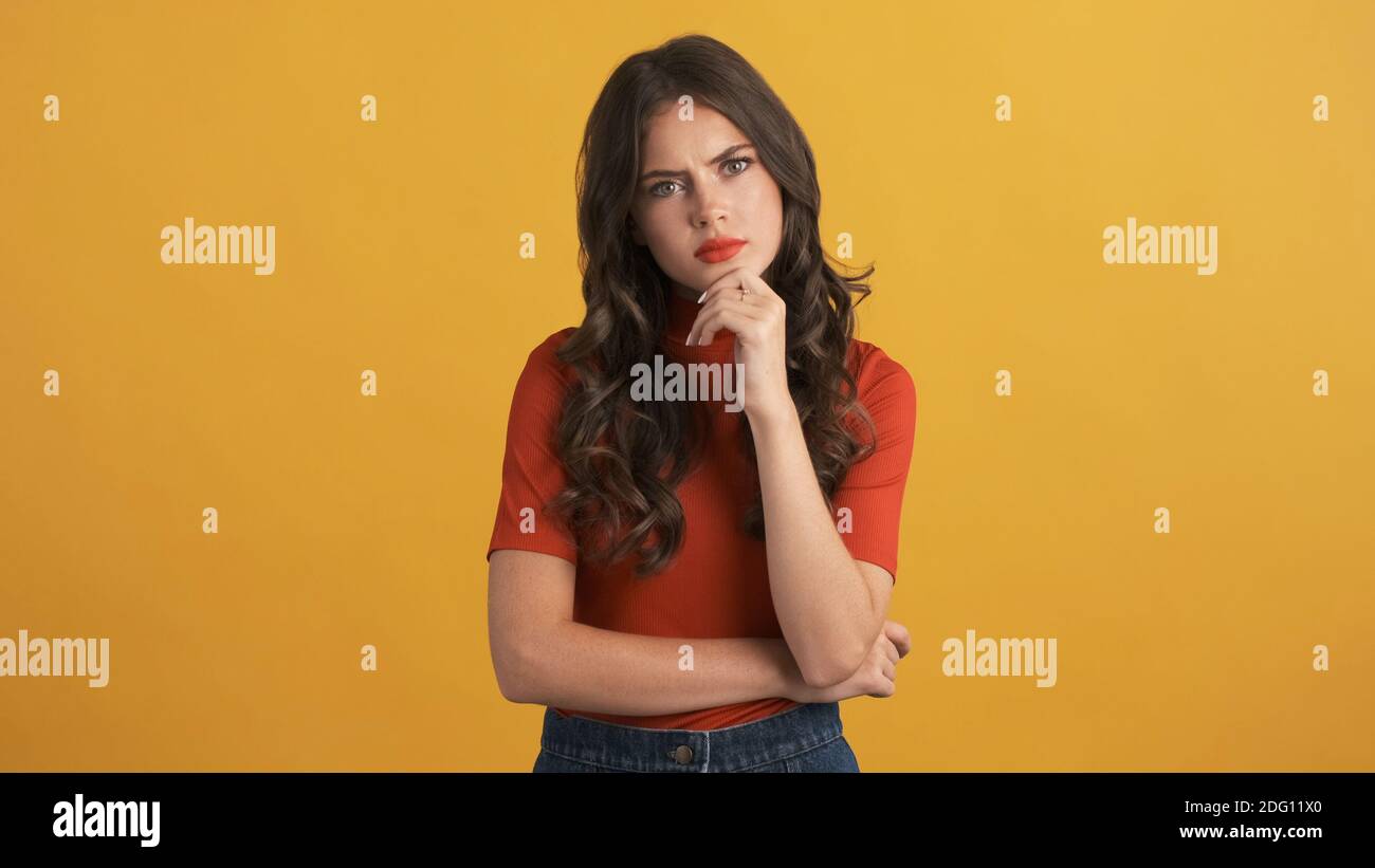 Serious thoughtful girl in red top angrily looking in camera over ...