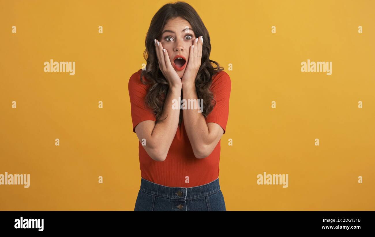 Attractive surprised girl in red top amazedly looking in camera over ...
