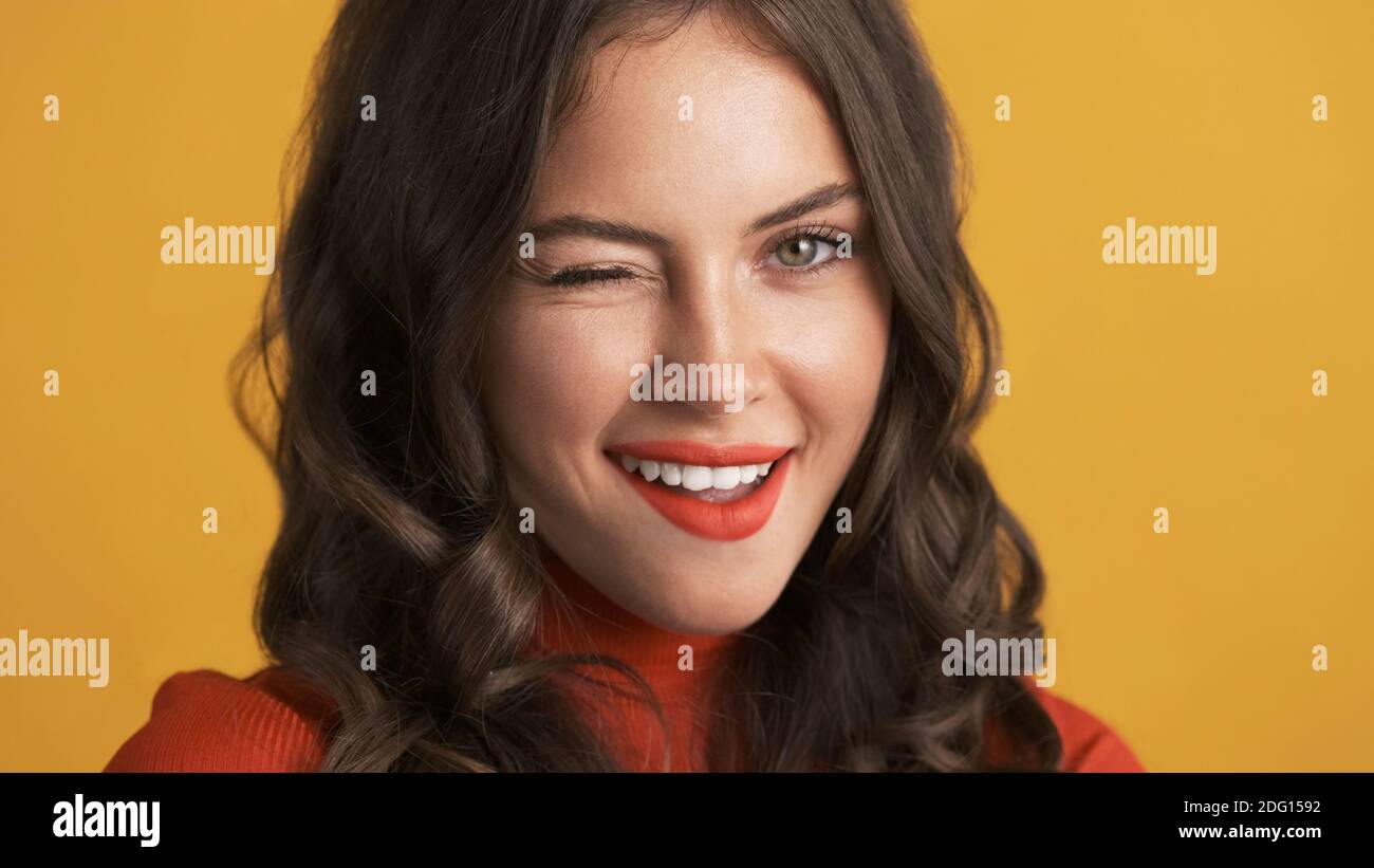 Close Up Attractive Brunette Girl With Red Lips Winking On Camera Over