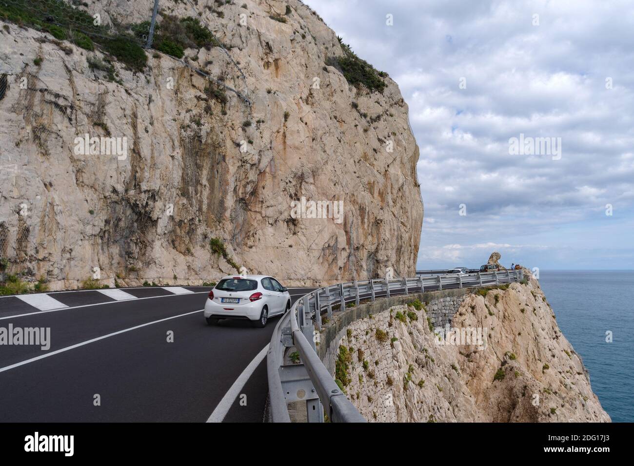 Car driving on a cliffside road and the sea along the coastline of ...