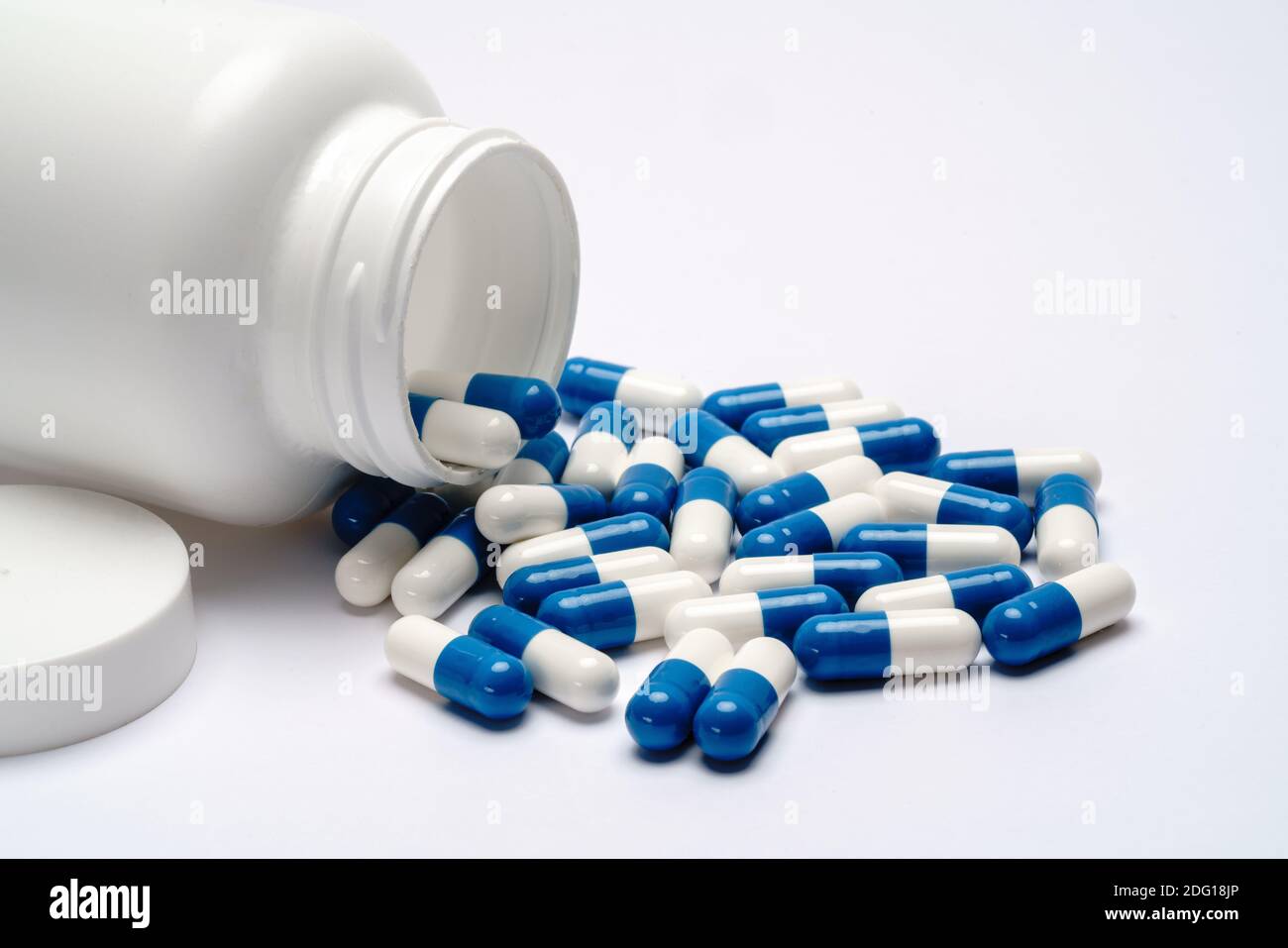 Medications capsules and white plastic bottle on light grey background ...