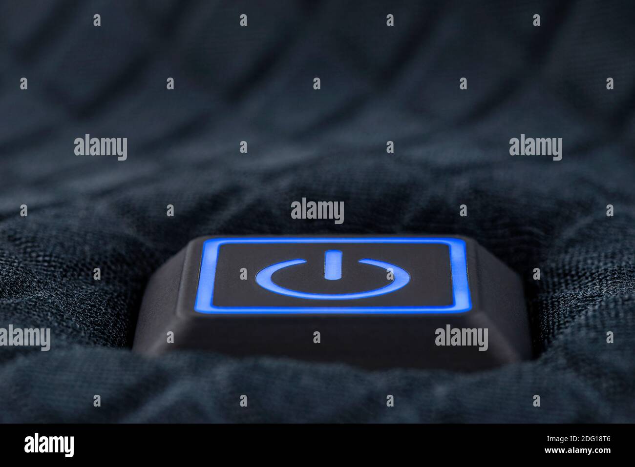 Macro shot of a plastic button with a blue power symbol, sewn into ...