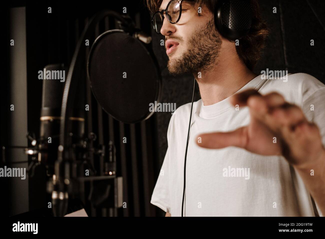 Close up young handsome male singer in headphones with professional ...