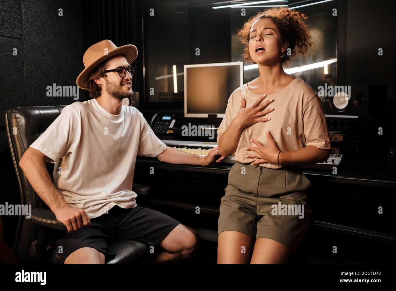 Attractive singer girl intently singing for musical producer in modern ...