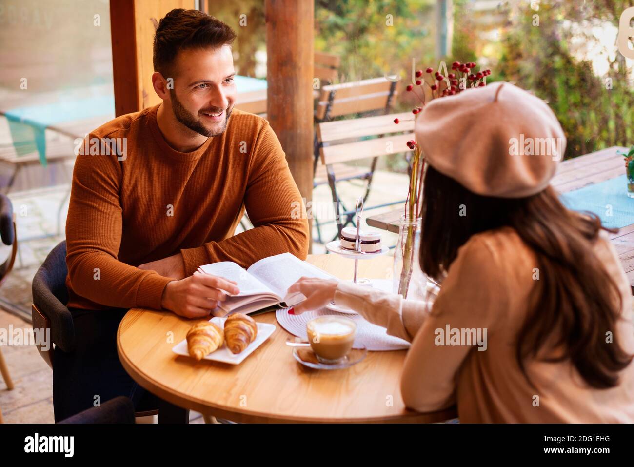 Lovely young couple sitting in a cafe and having breakfast while ...