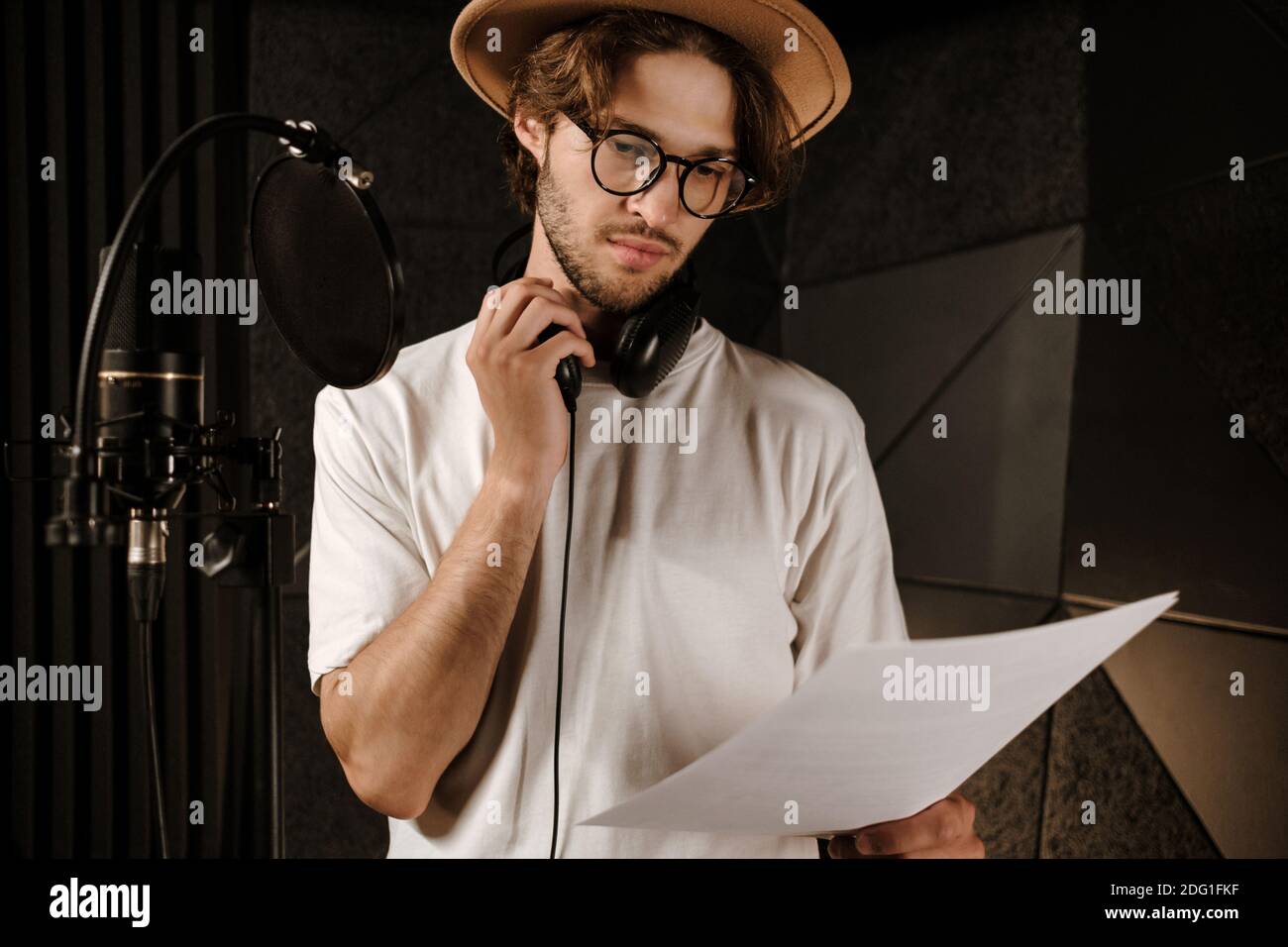 Young confident male singer thoughtfully reading text of new song ...
