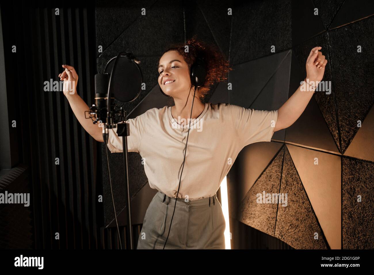 Beautiful female musician in headphones sensually dancing and singing ...