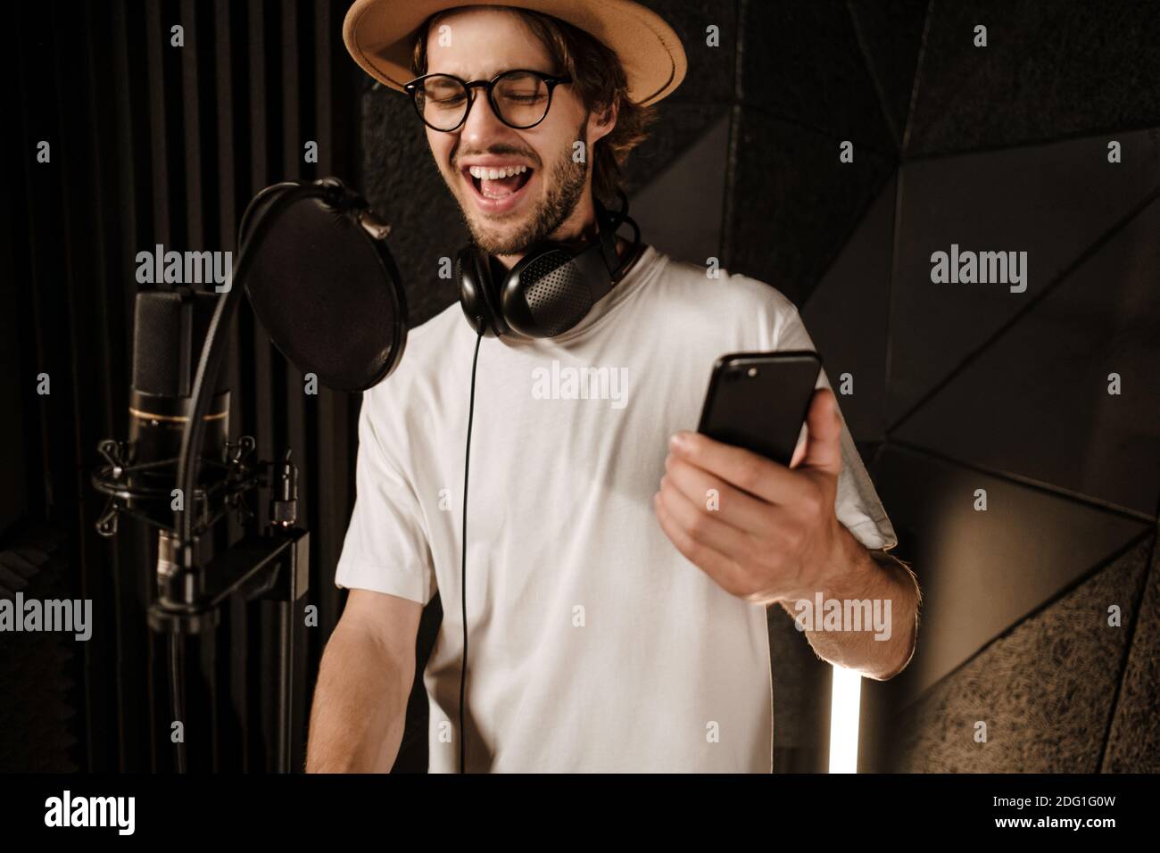 Young attractive male singer with smartphone emotionally singing in ...