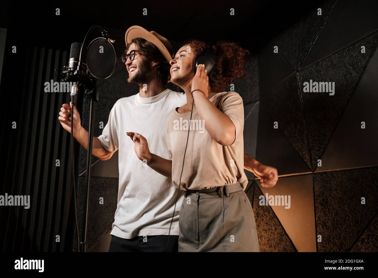 Young attractive man and woman joyfully singing together in sound ...