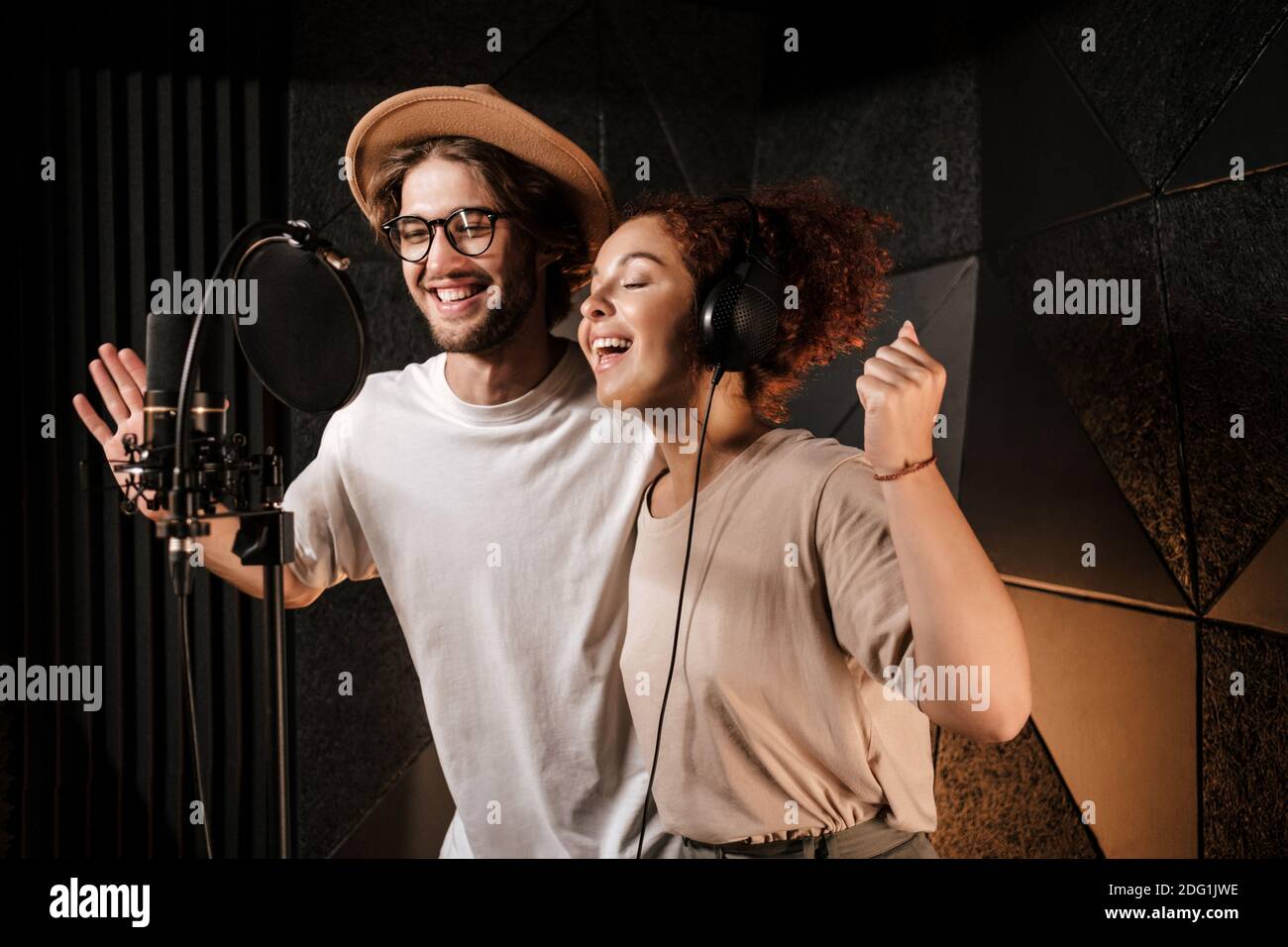 Young attractive musicians happily singing together recording new song ...