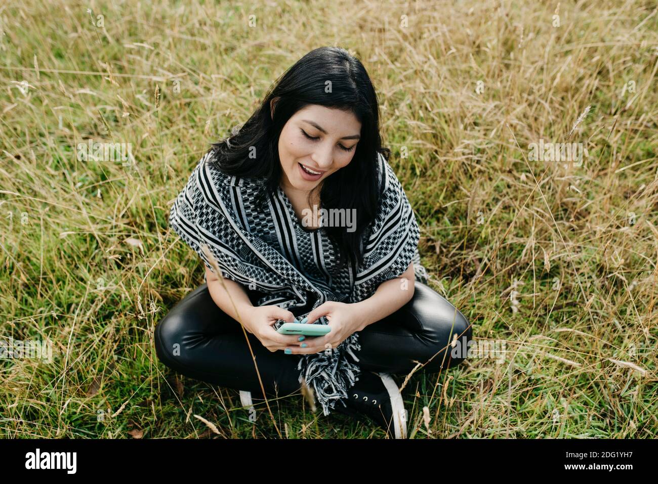 Portrait of a cute hispanic woman in the park writing on the phone ...